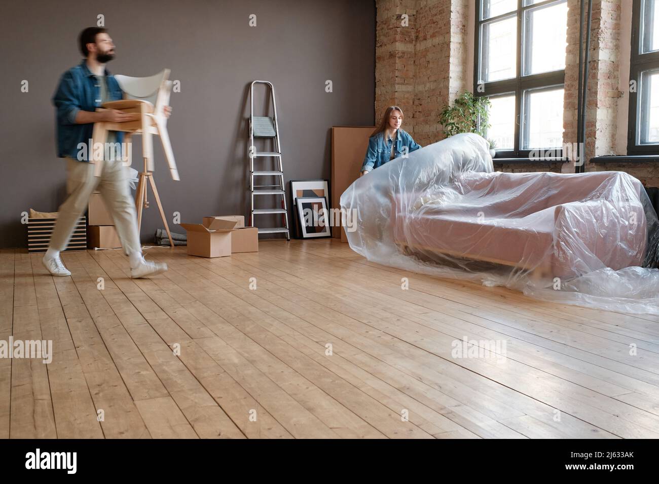 Horizontal long shot of young man and woman getting ready to move to ...