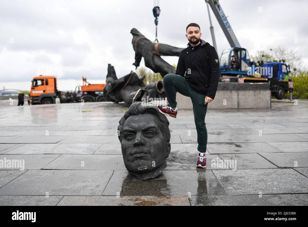 A man poses for photos while stepping on the dismantled Soviet Union ...