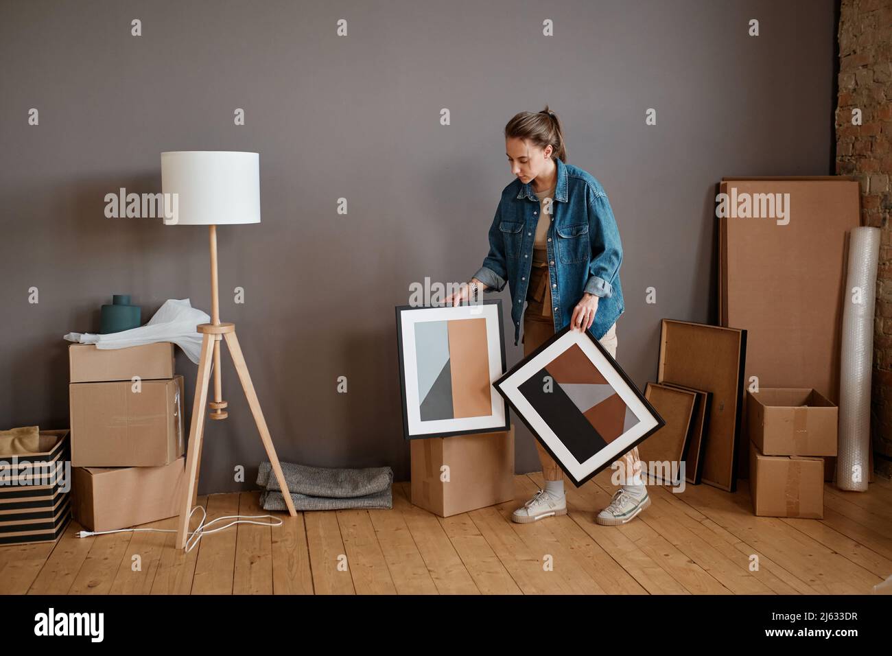 Horizontal shot of young woman moving to new house taking abstract ...