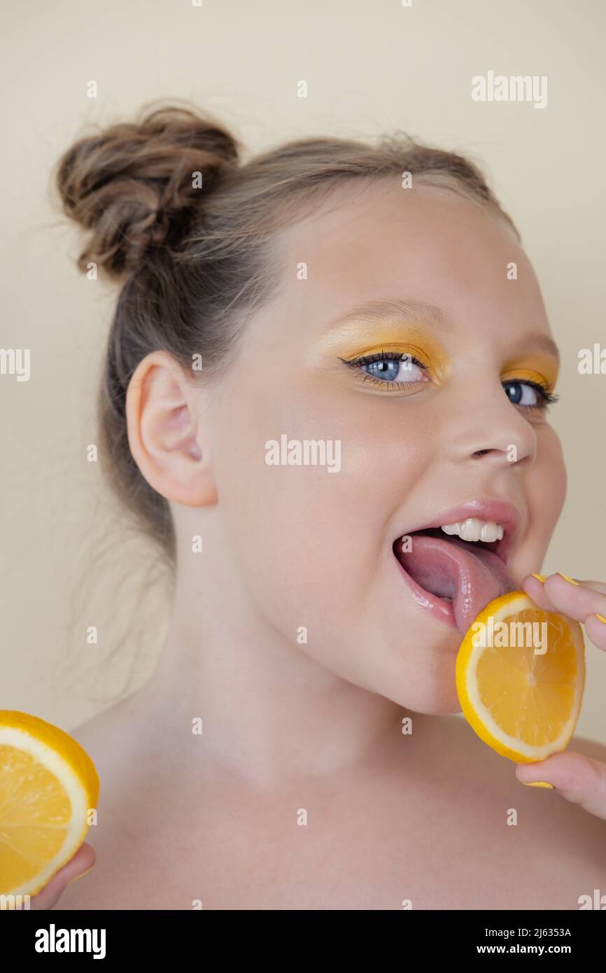 sweet cute girl school age holding a ripe fresh lemon on yellow ...