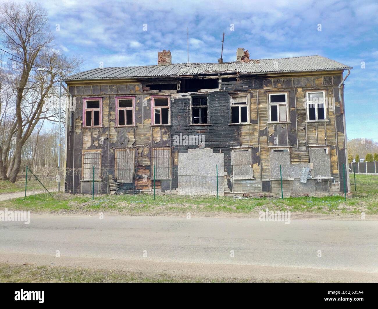 Old wooden half burned house. Destroyed abandoned house with blue sky ...