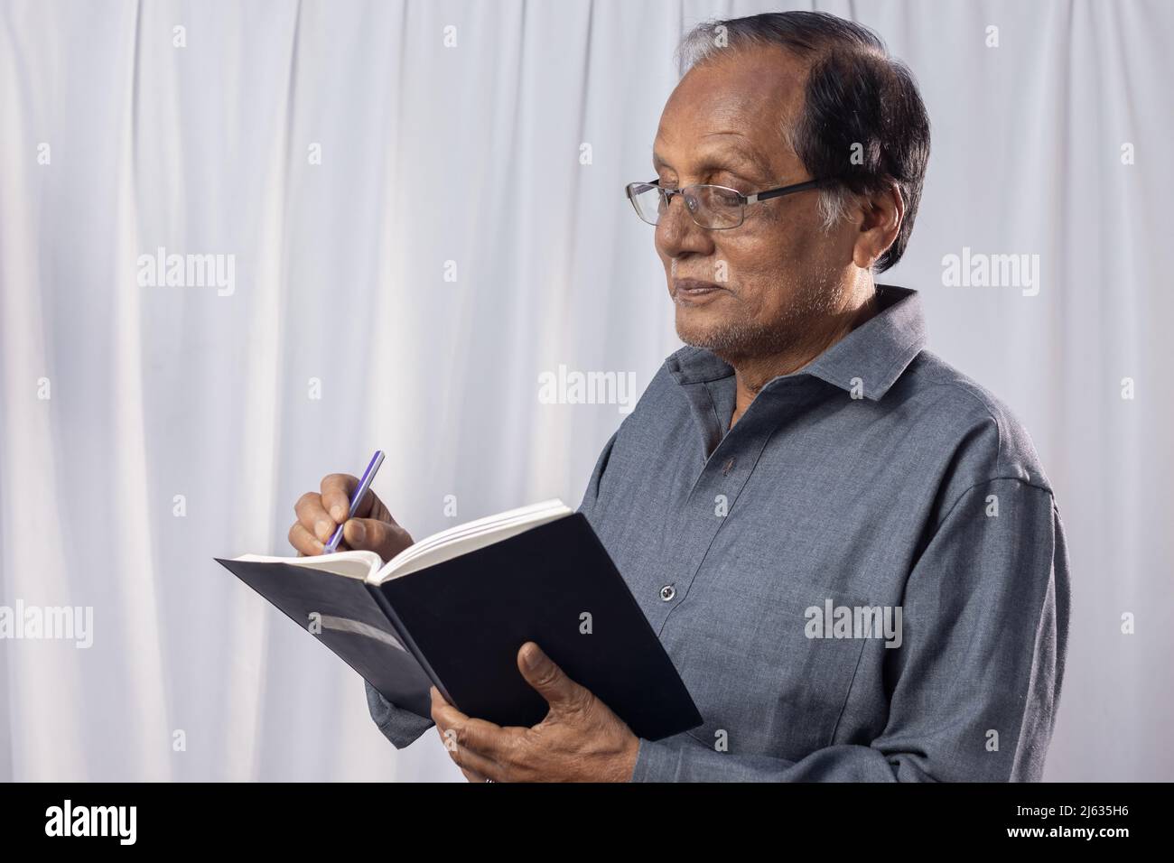 An old Indian man taking notes standing on white background Stock Photo ...