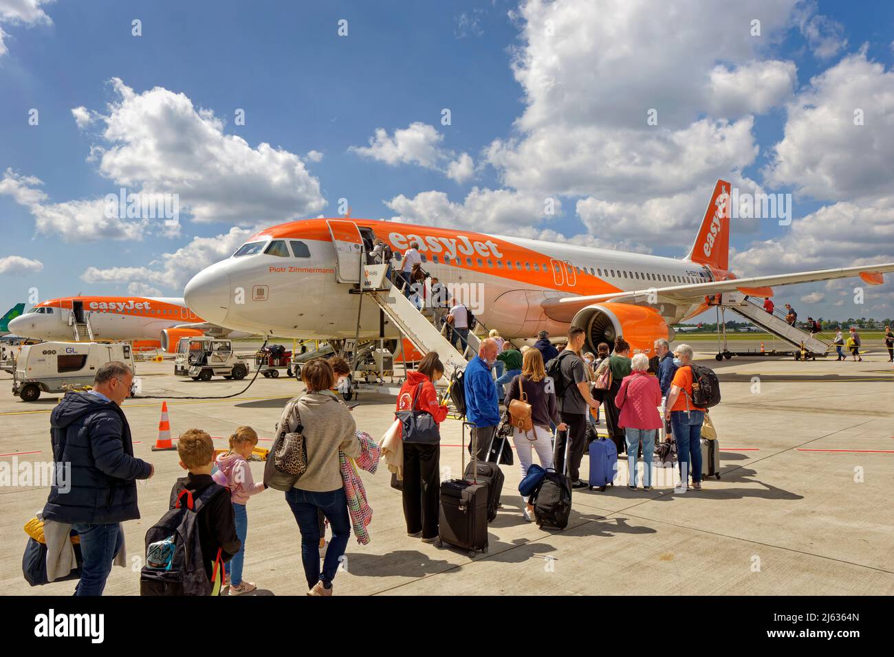Passengers boarding easyJet aircraft by stairway from airport apron ...