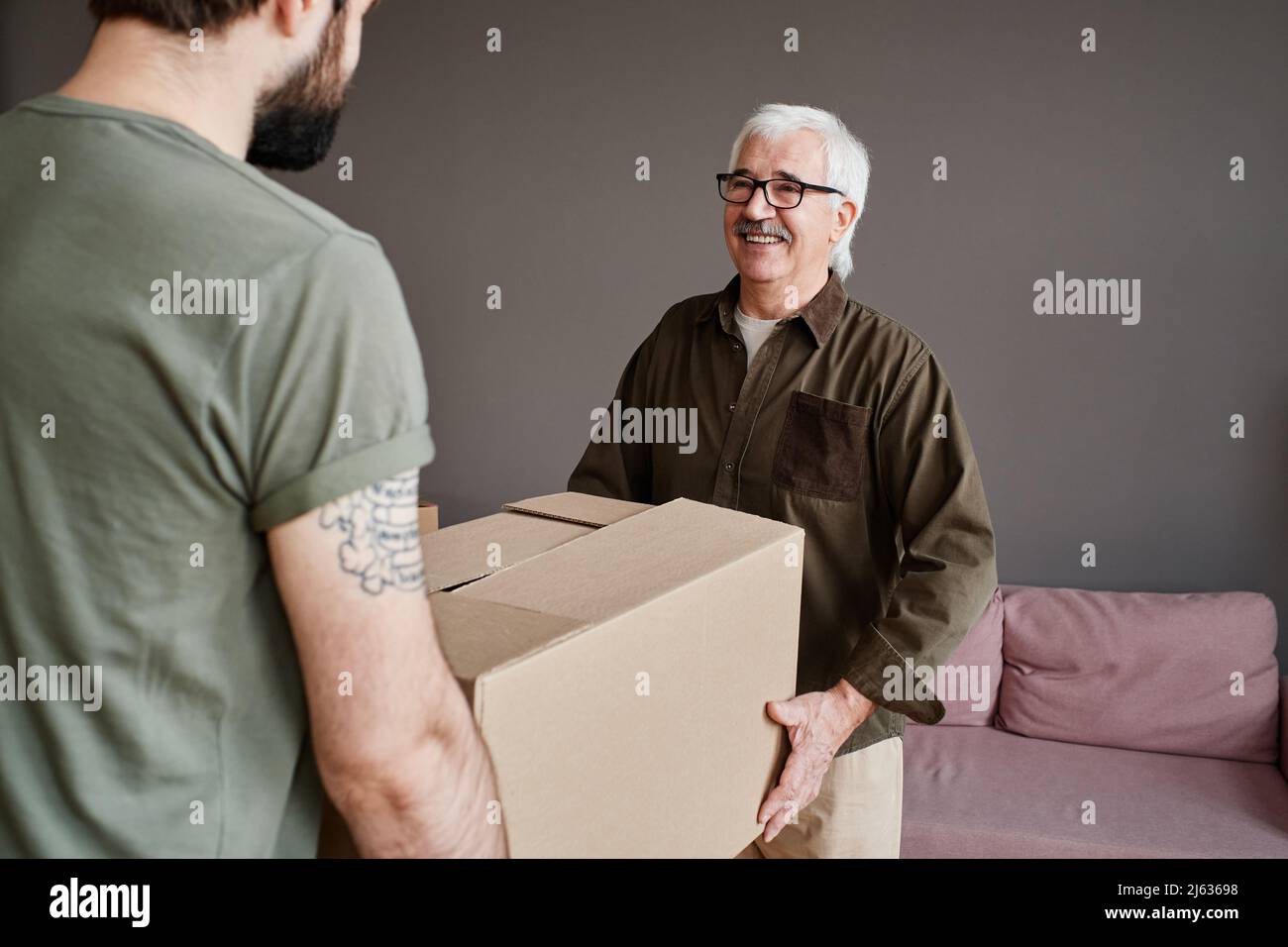 Horizontal medium shot of young man helping his senior father with ...