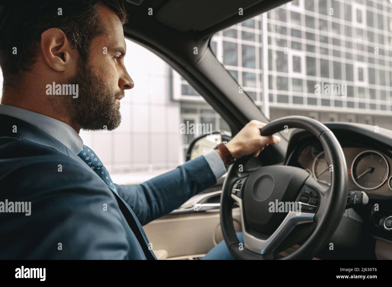 Confident adorable business man in suit driving the automobile in the ...