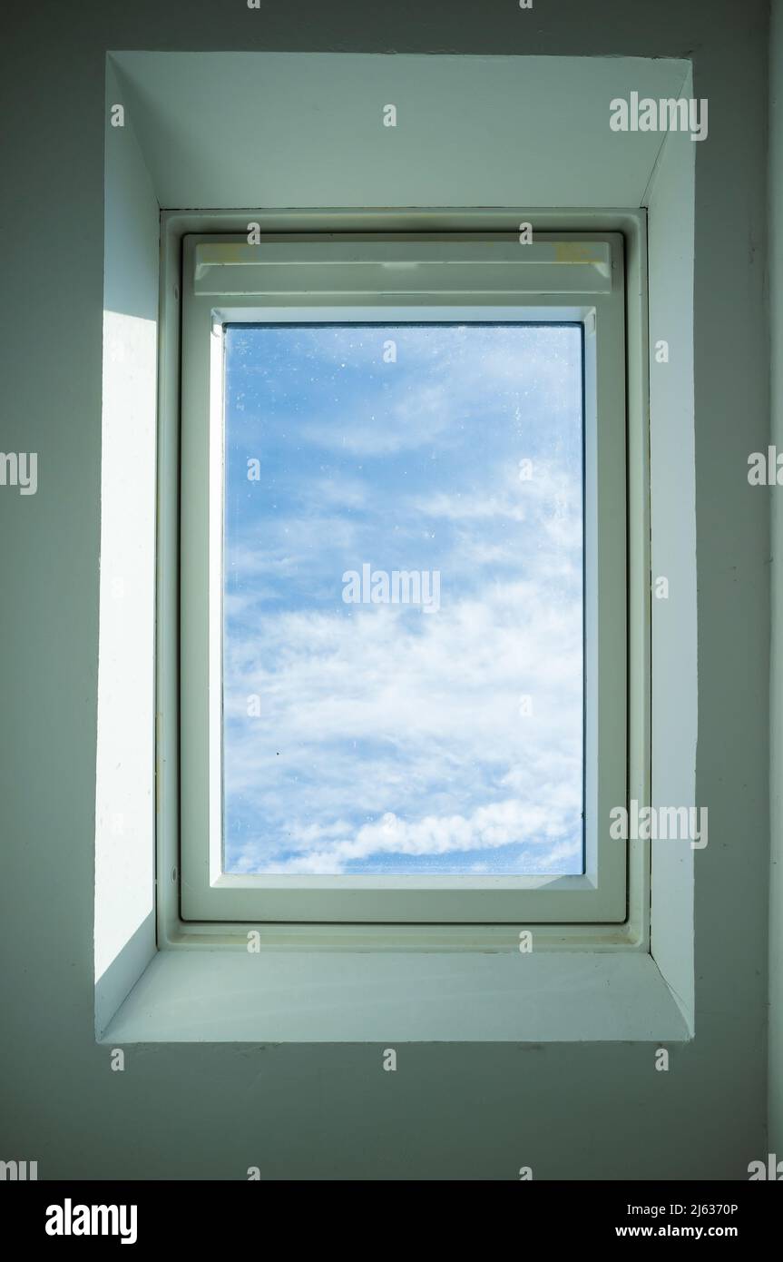 Closed roof window through which you can see the blue sky and white ...