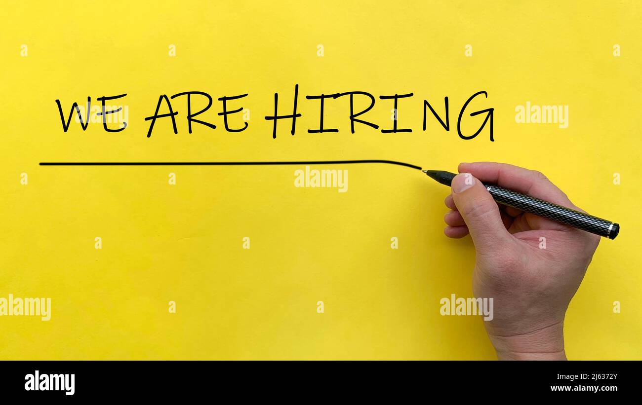 Hand writing we are hiring on yellow cover background. Job vacancy and ... Hand writing we are hiring on yellow cover background. Job vacancy and ...