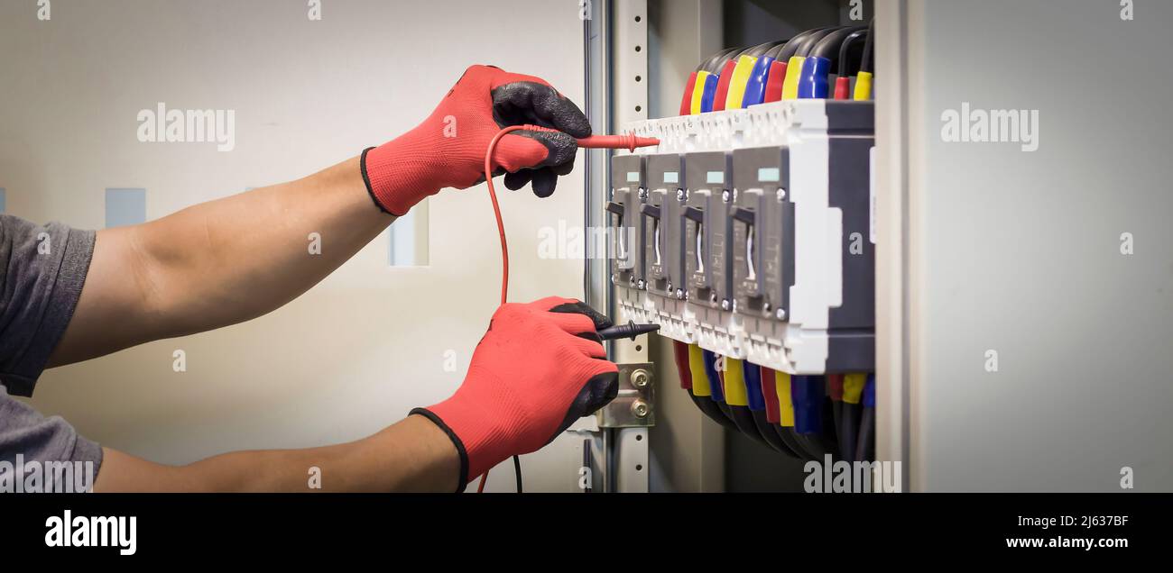 Electrical engineers check electrical control devices with a multimeter ...