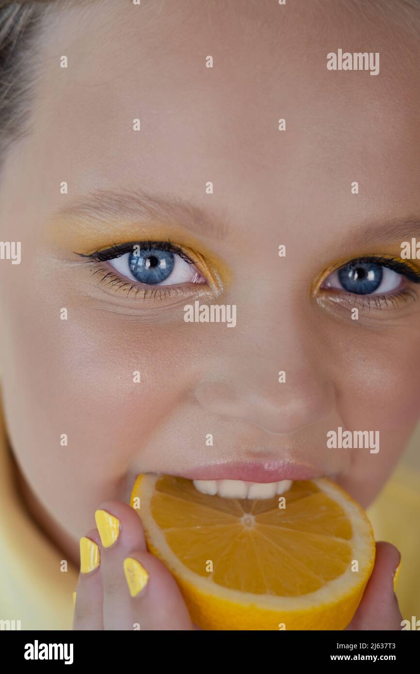 sweet cute girl school age holding a ripe fresh lemon on yellow ...