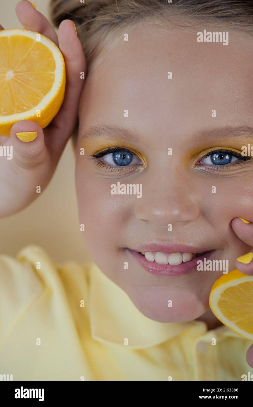 sweet cute girl school age holding a ripe fresh lemon on yellow ...