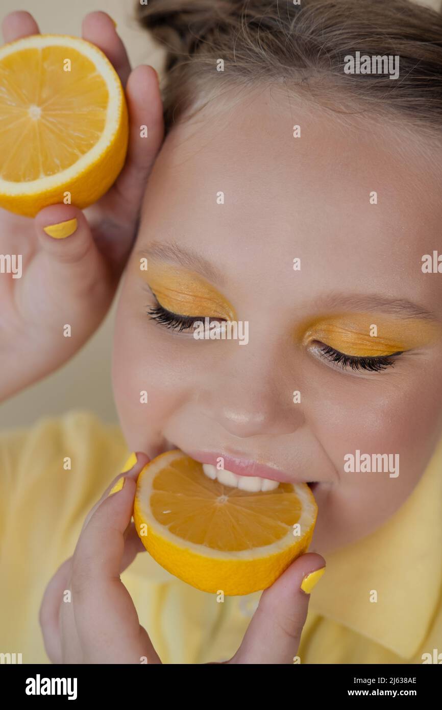 charming tween girl with slices of ripe lemon on yellow background ...