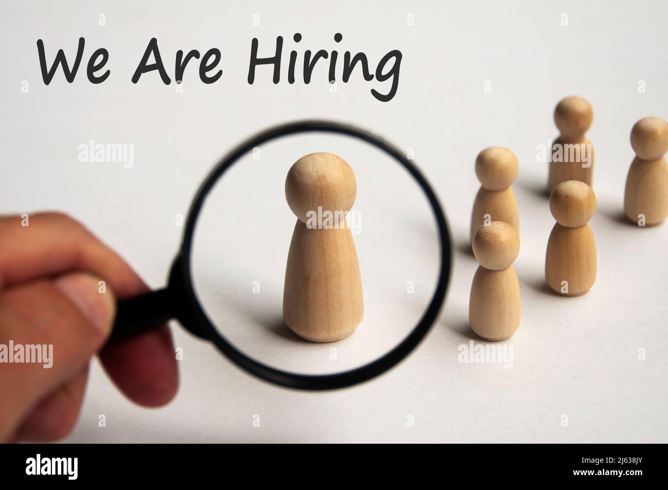 Hand holding a magnifying glass focusing on wooden figure from the ...