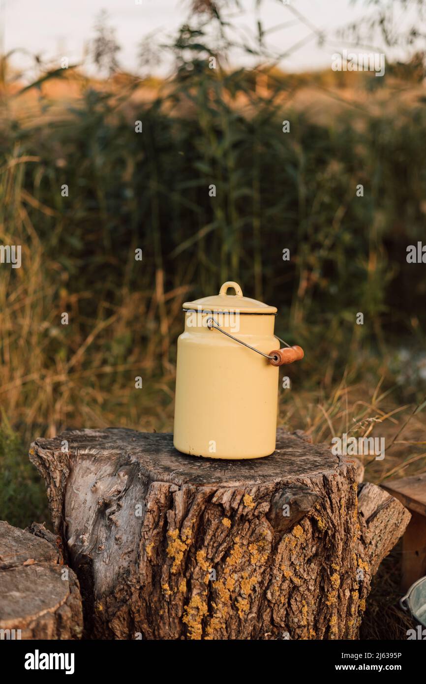 Yellow metal milk container stands on a stump in the village Stock ...