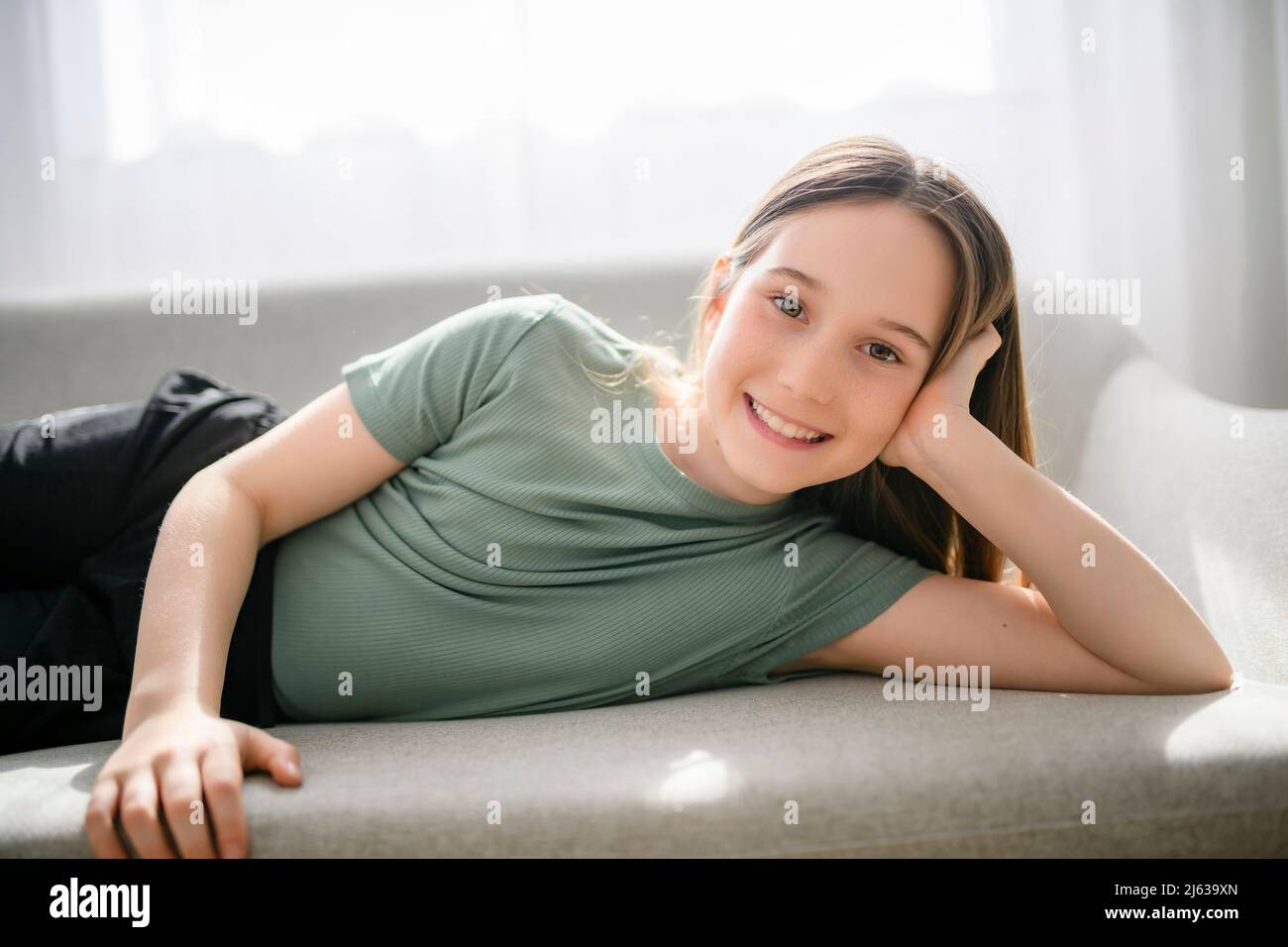 Beautiful pre teen girl relaxing on the sofa at home Stock Photo - Alamy