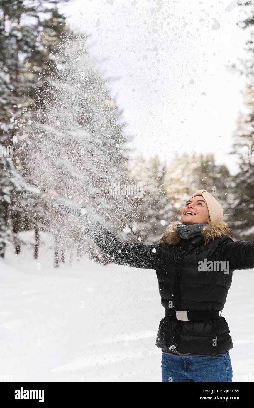 Cheerful woman throwing snow into the air during cold winter day Stock ...