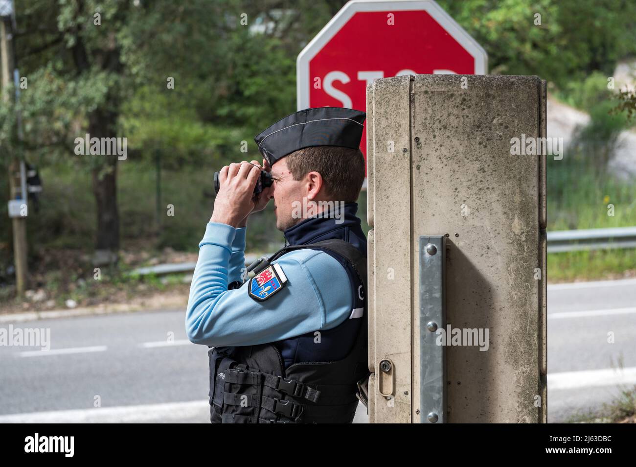 A police officer on the side of the road uses radar binoculars to ...