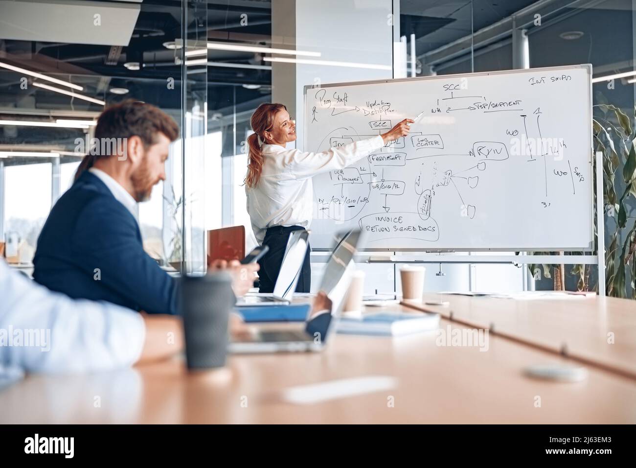 Skilled smiling female leader coaching interested business people ...