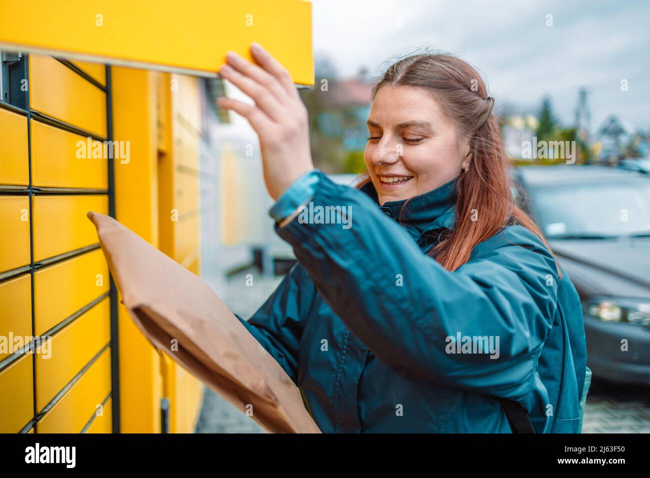 Caucasian woman send or receive parcel with self service post terminal ...
