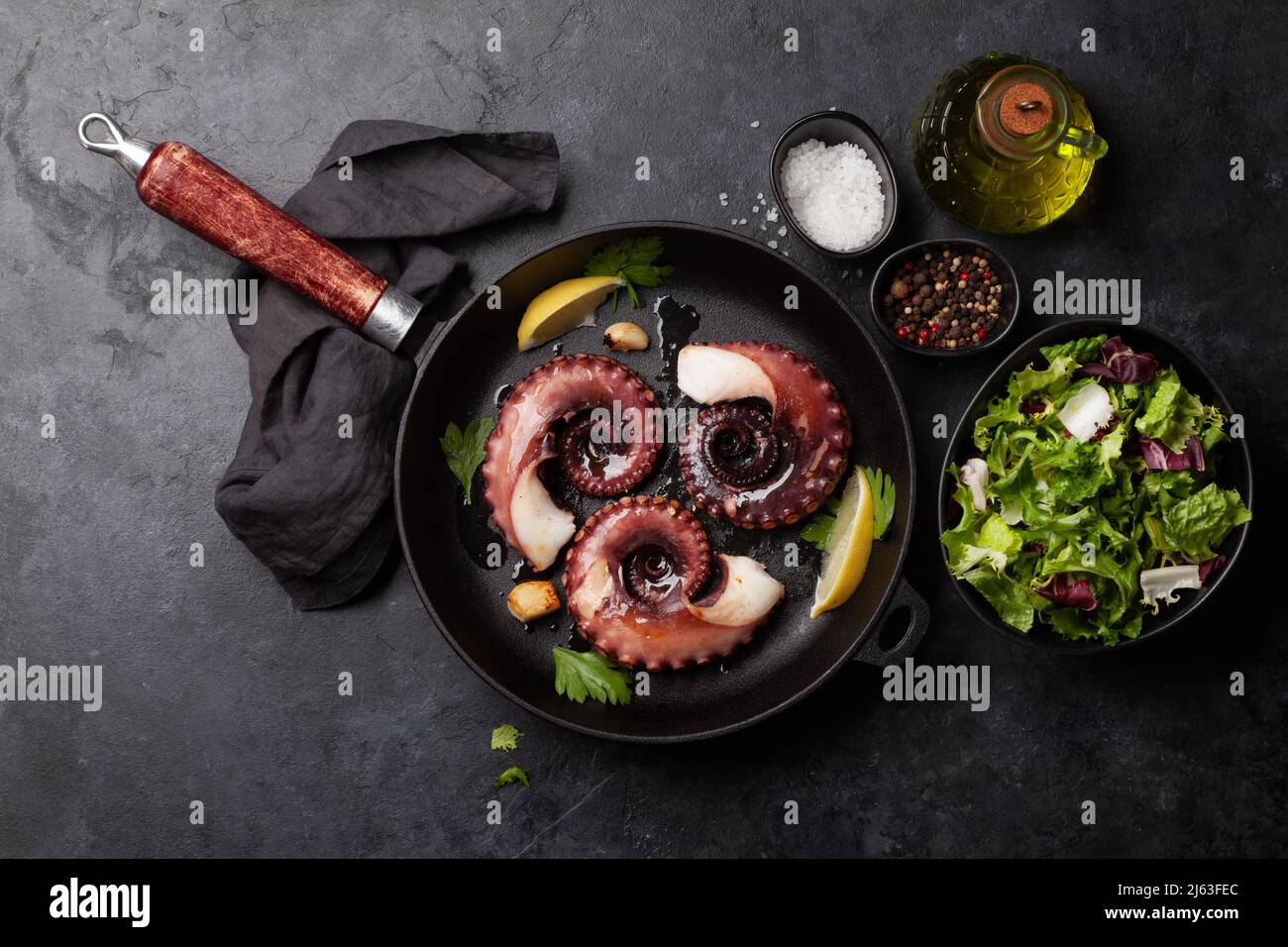 Grilled octopus with herbs and spices on frying pan. Top view flat lay ...