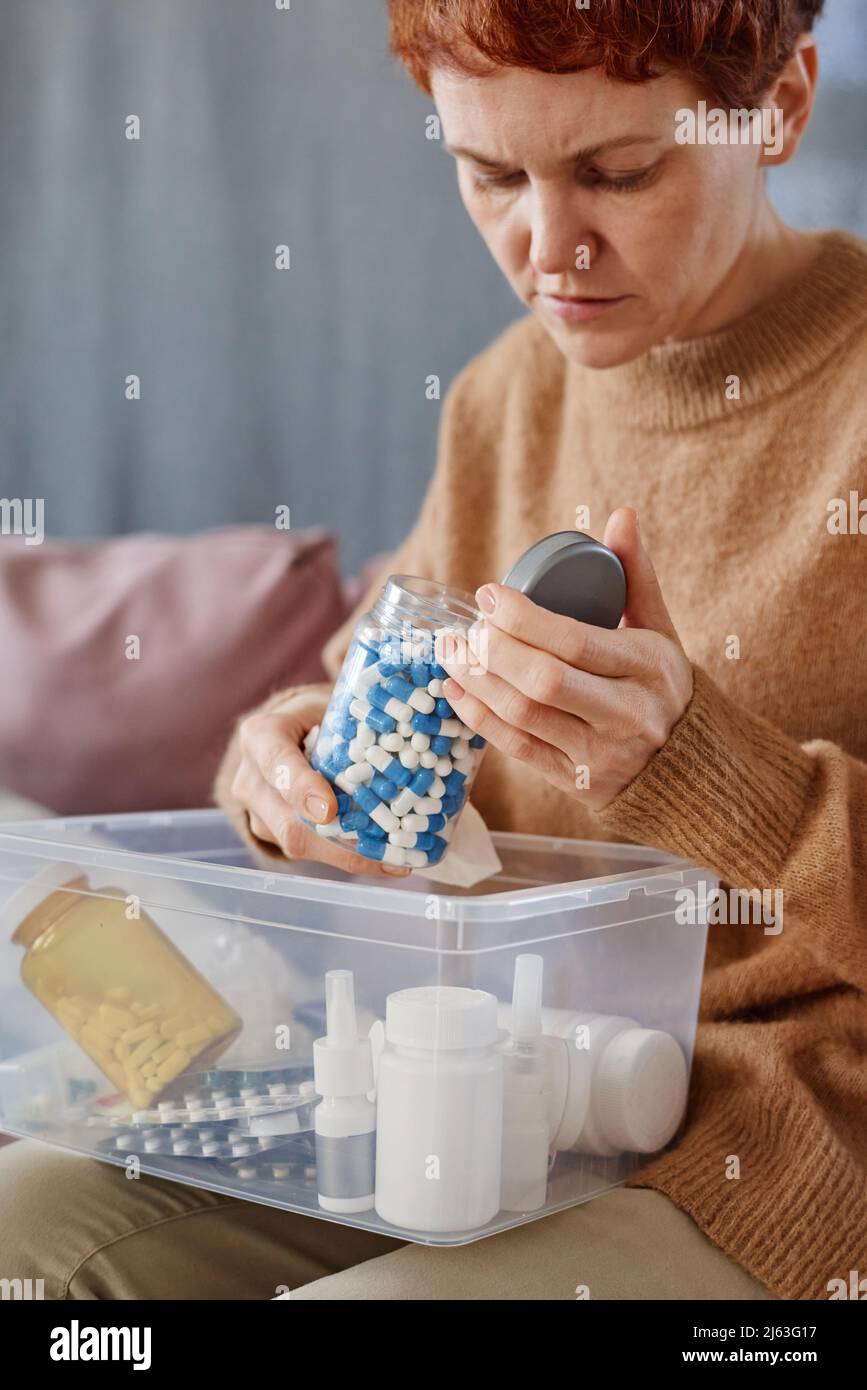Vertical medium shot of mature woman suffering flu symptoms sitting on ...