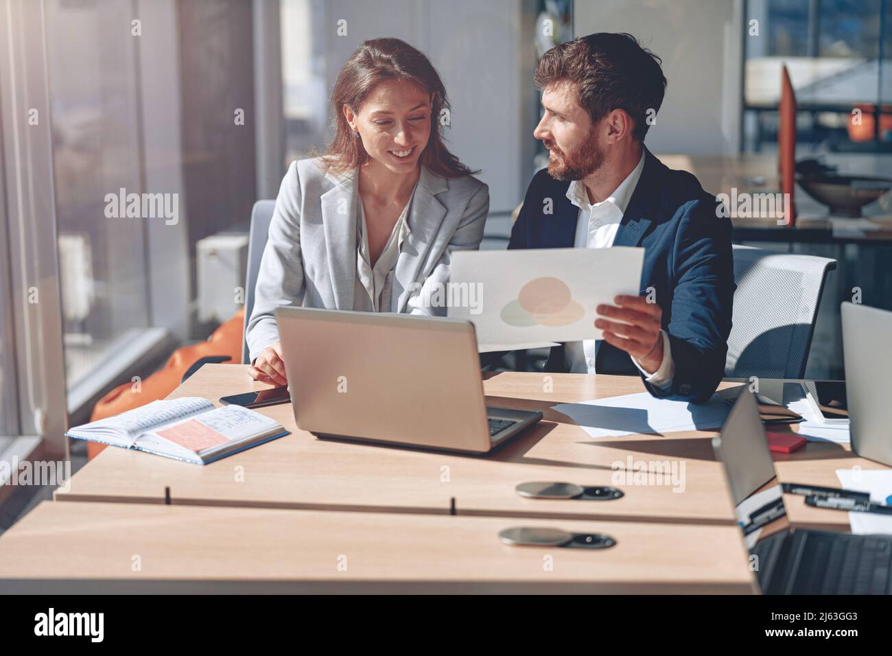 Two business people in modern office explaining statistics data to each ...