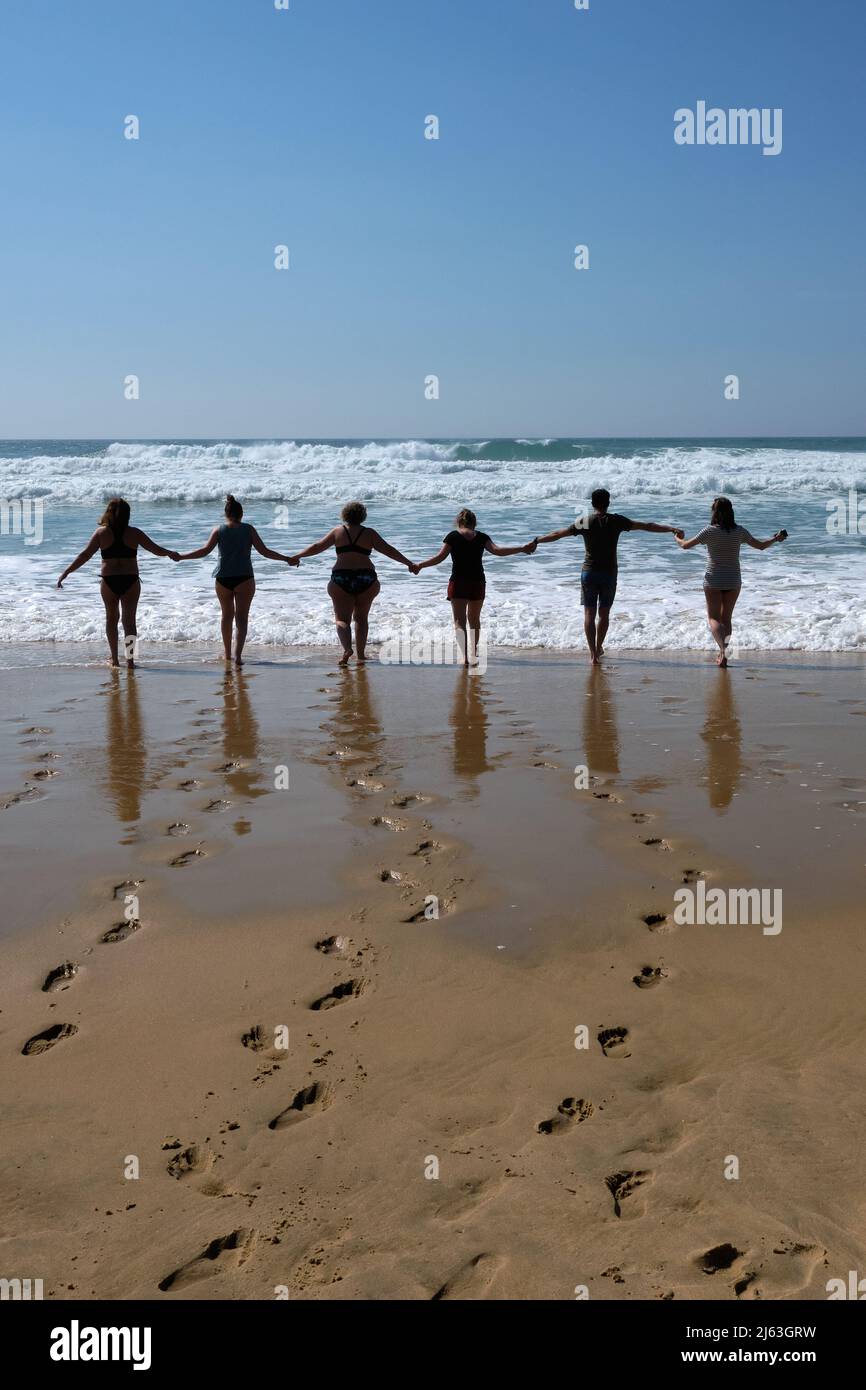 Vertical photograph of a group of friends holding hands on a beach ...