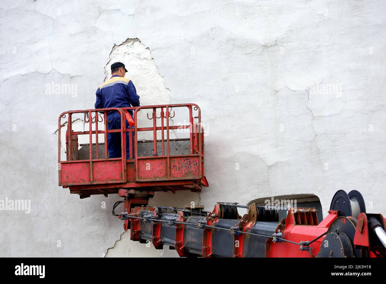 Worker in hydraulic lifting ramp repair the building wall. Builder on ...