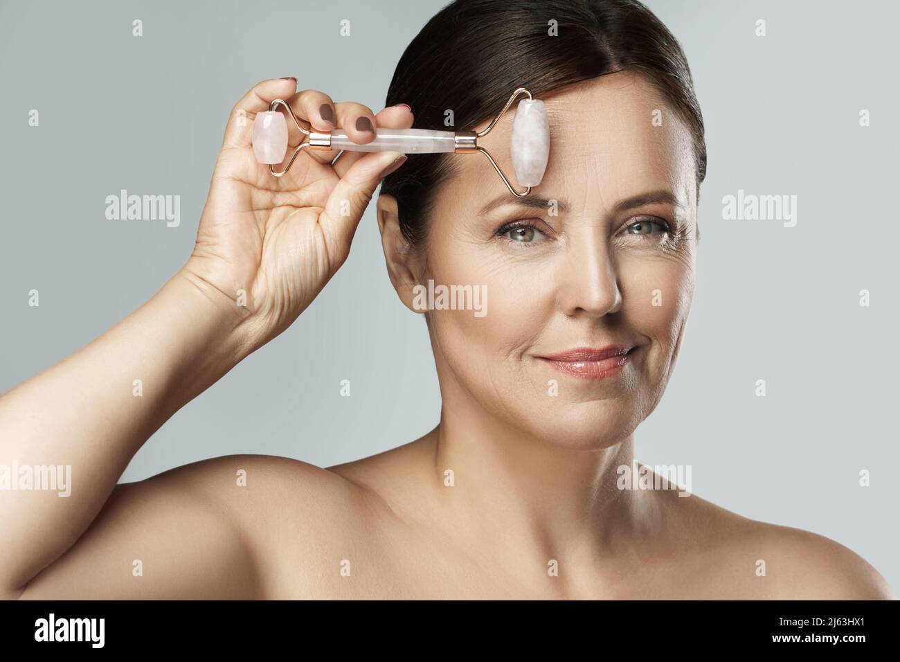 Senior woman using face roller hi-res stock photography and images - Alamy