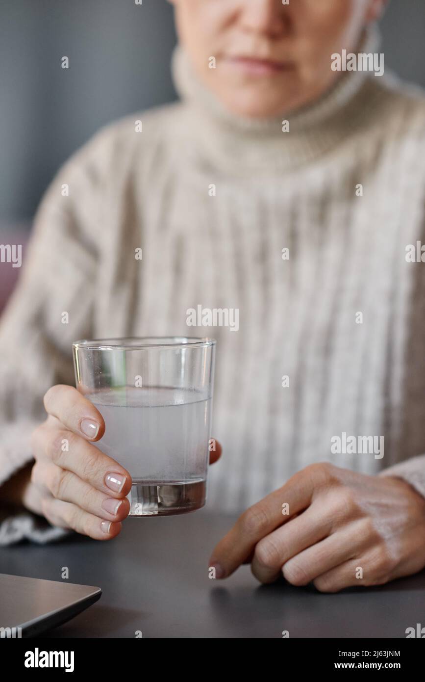 Vertical shot of mature woman having cold wearing sweater sitting at ...