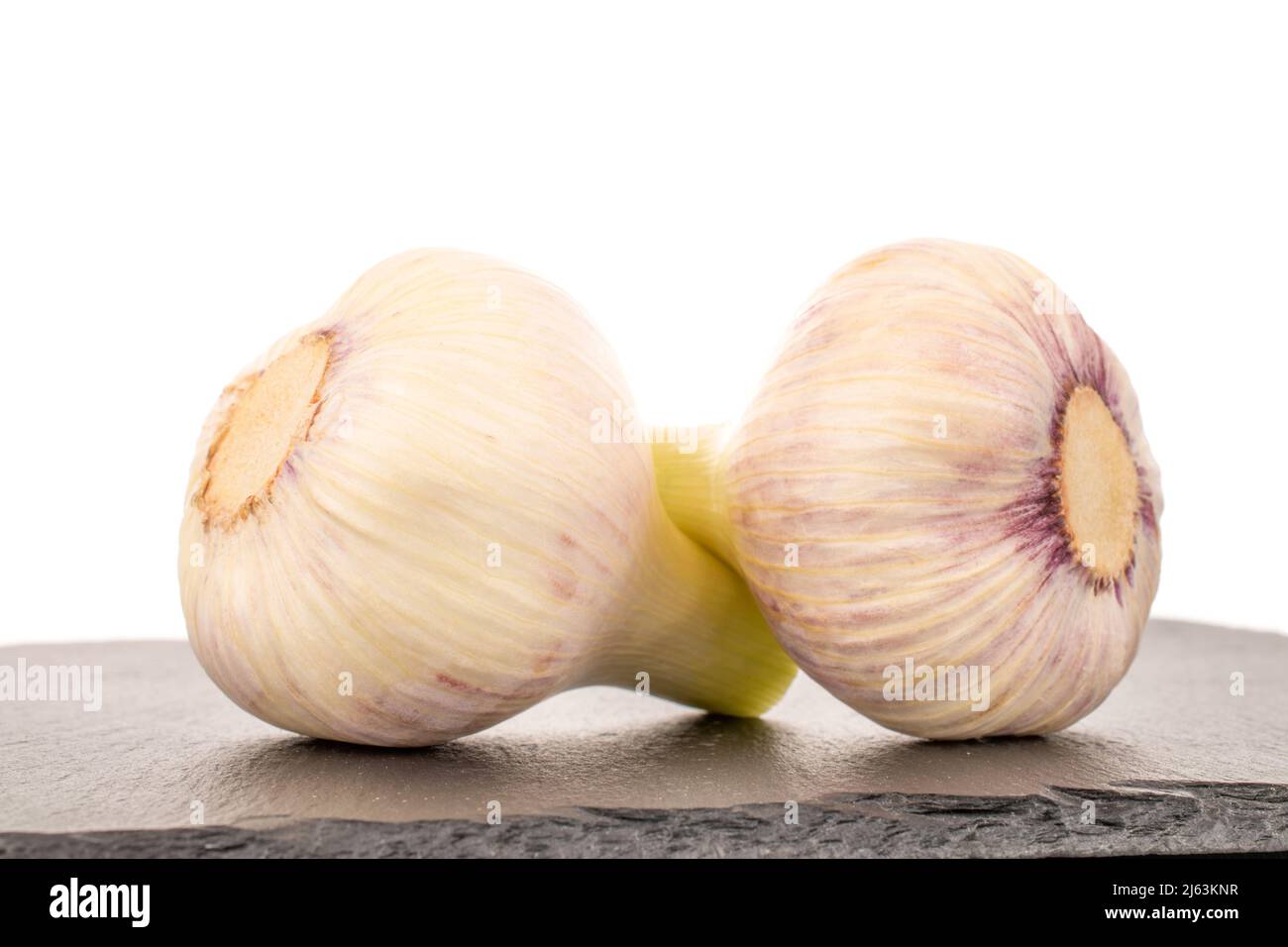 Two heads of early garlic on a slate stone, macro, isolated on a white ...