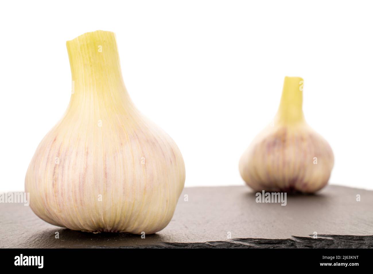 Two heads of early garlic on a slate stone, macro, isolated on a white ...