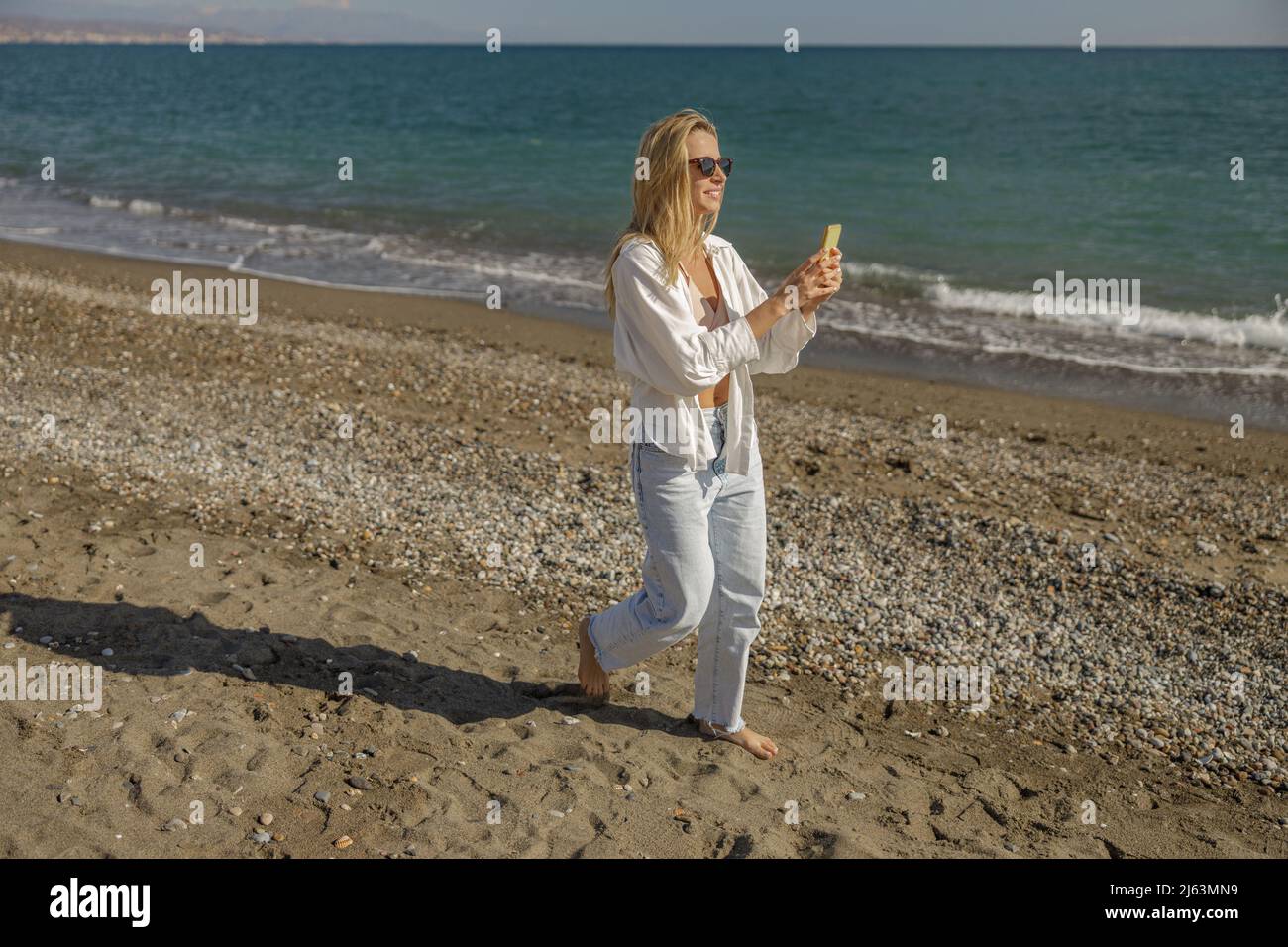 Full length shot of lady using smartphone while having a walk along the ...