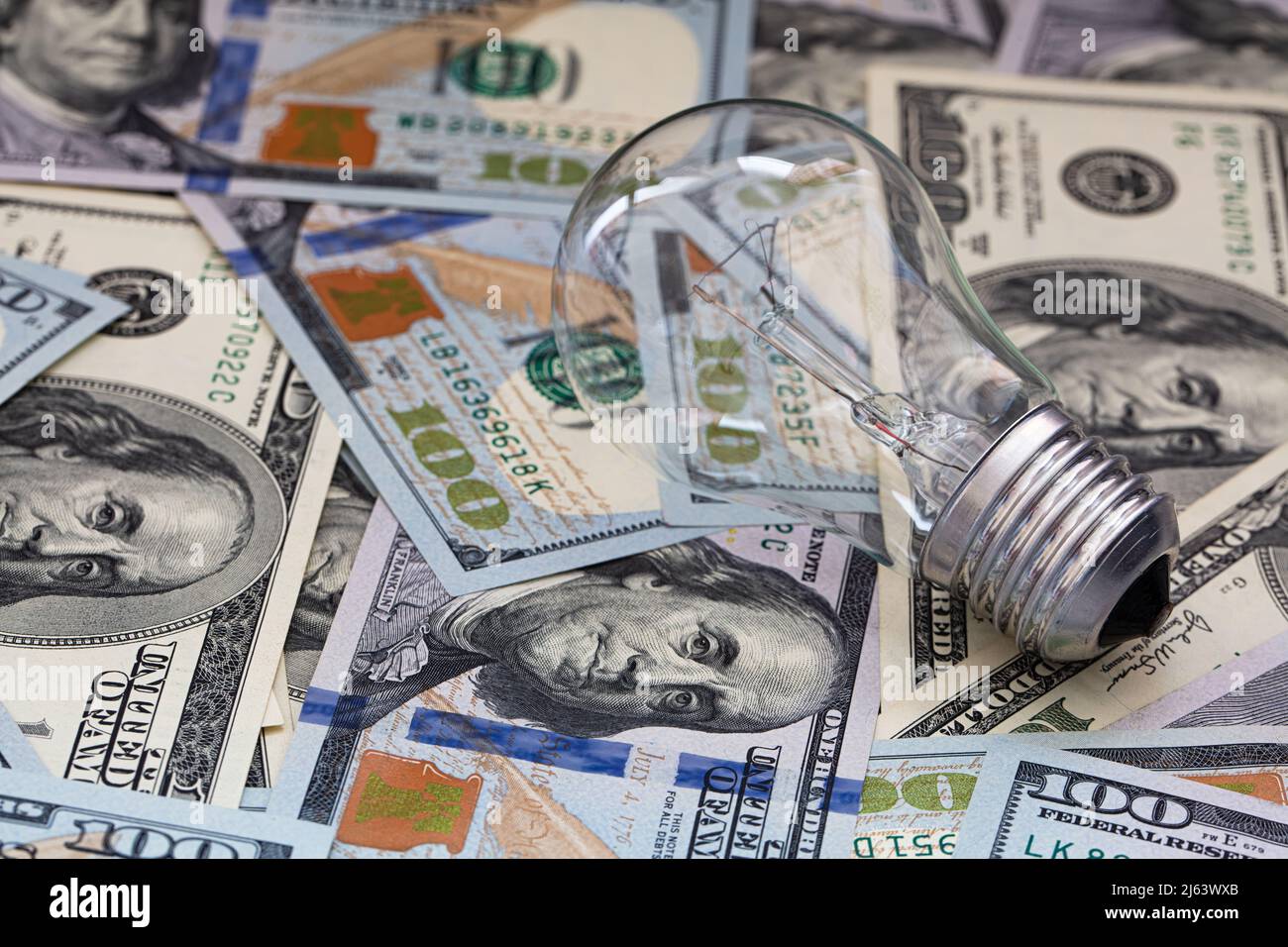Incandescent light bulb on US 100 dollar background for desing purpose ...