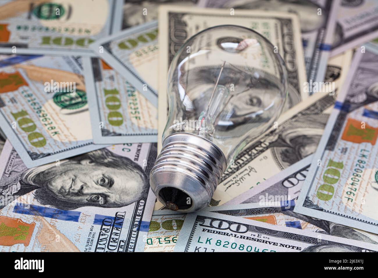 Incandescent light bulb on US 100 dollar background for desing purpose ...