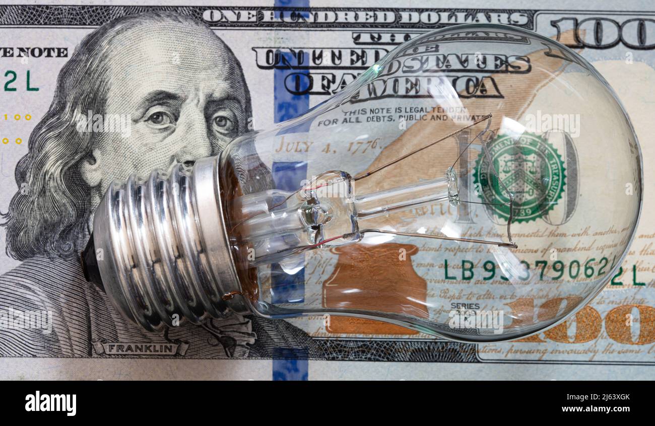 Incandescent light bulb on US 100 dollar background for desing purpose ...