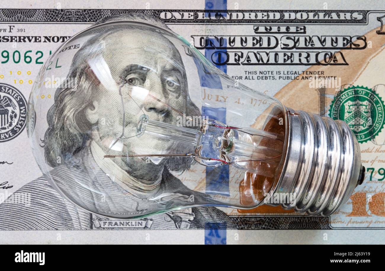 Incandescent light bulb on US 100 dollar background for desing purpose ...