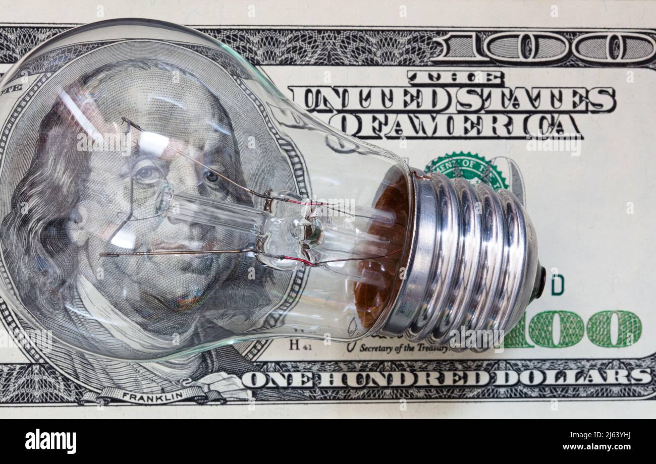 Incandescent light bulb on US 100 dollar background for desing purpose ...