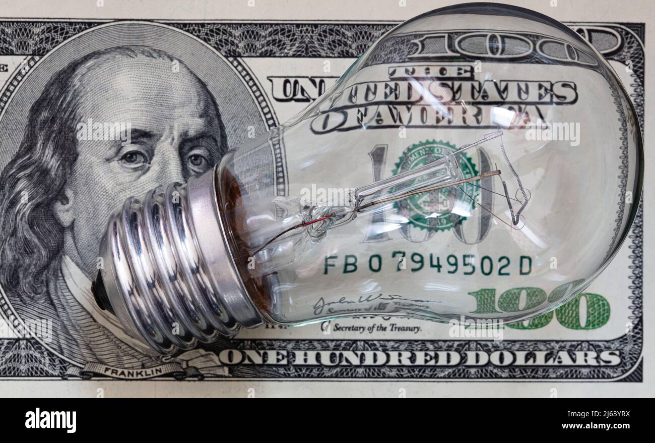 Incandescent light bulb on US 100 dollar background for desing purpose ...