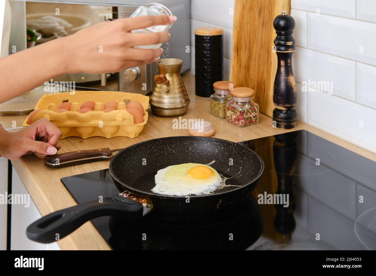Closeup view of female hand seasoning scrambled eggs with salt on a pan ...