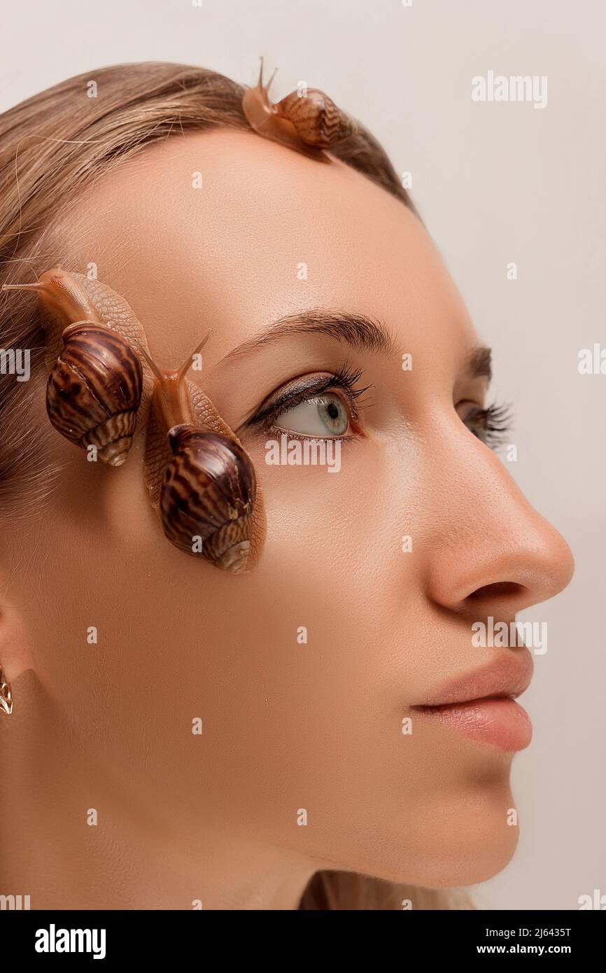 Large and small snails of achatina crawl on the face and neck of a ...