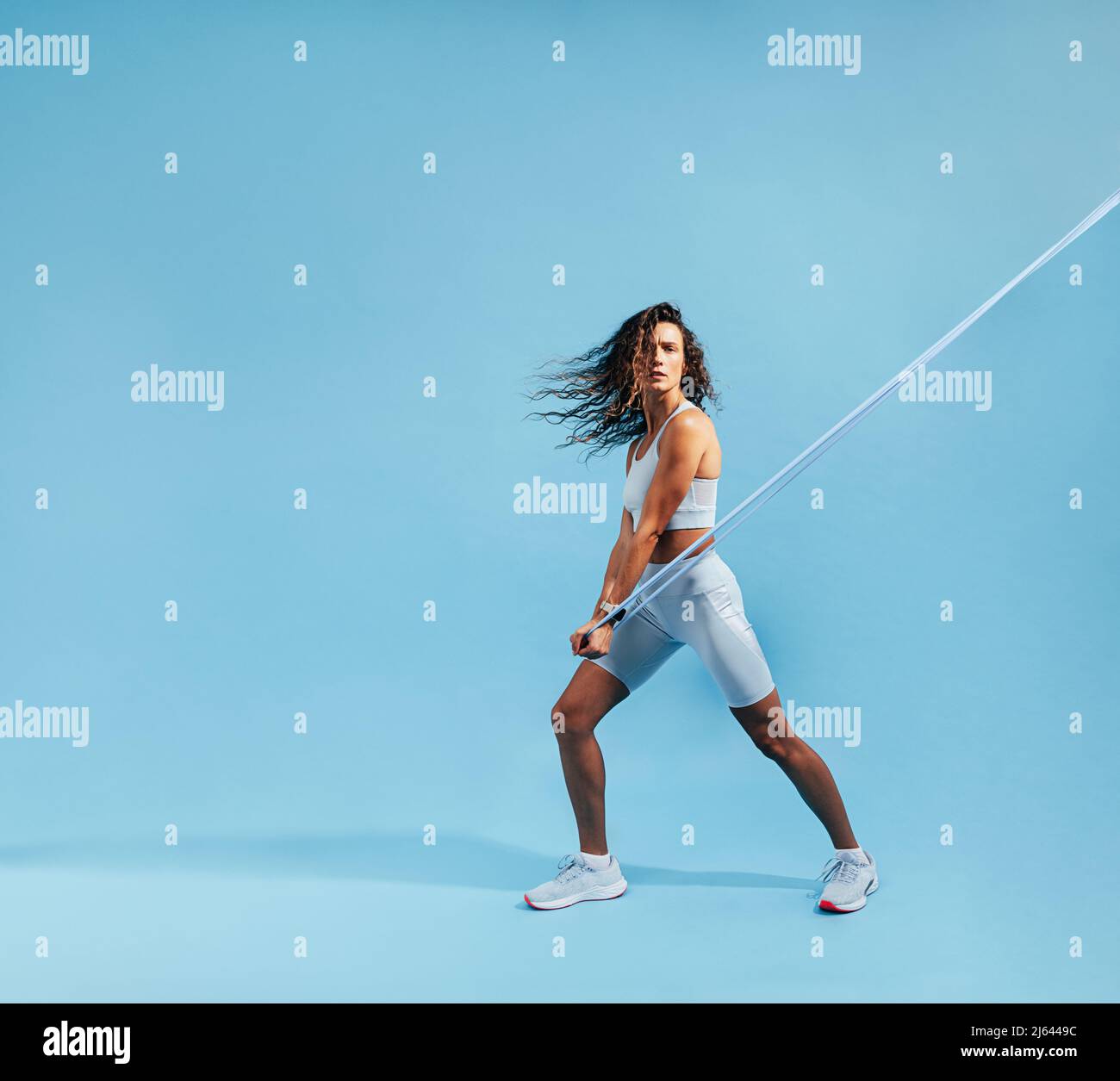 Female athlete doing intense stretching exercises with elastic band ...