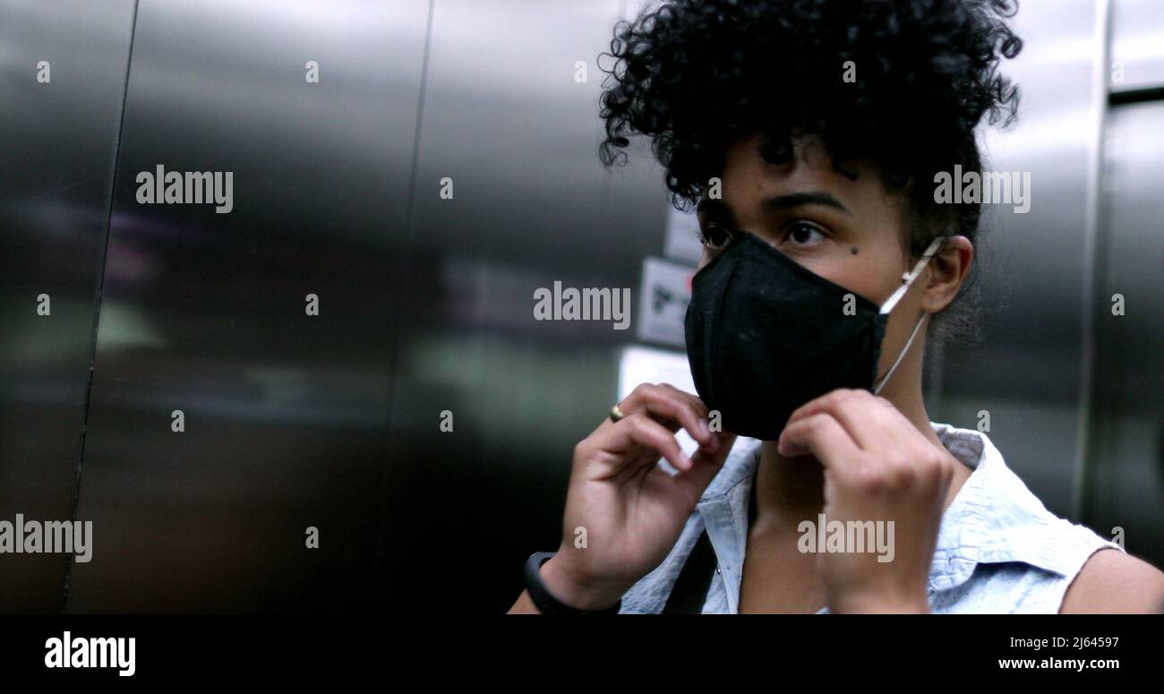 Black woman putting covid-19 face mask inside elevator Stock Photo - Alamy