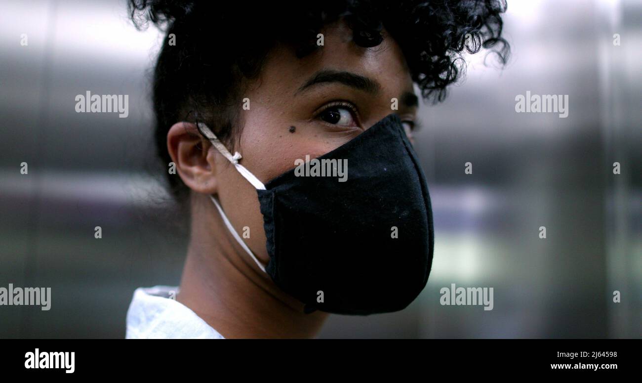 Black woman putting covid-19 face mask inside elevator Stock Photo - Alamy