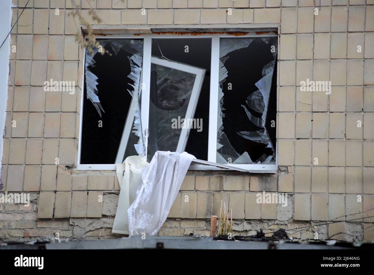 A broken window is pictured inside a residential building damaged as a ...