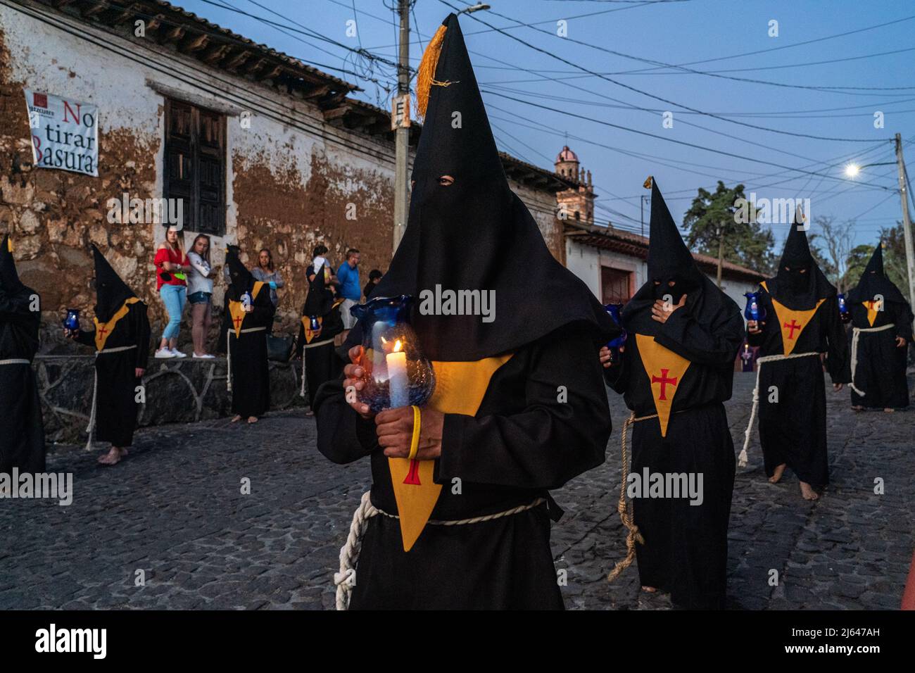Roman Catholic hooded penitents wearing traditional capirotes, hold a ...