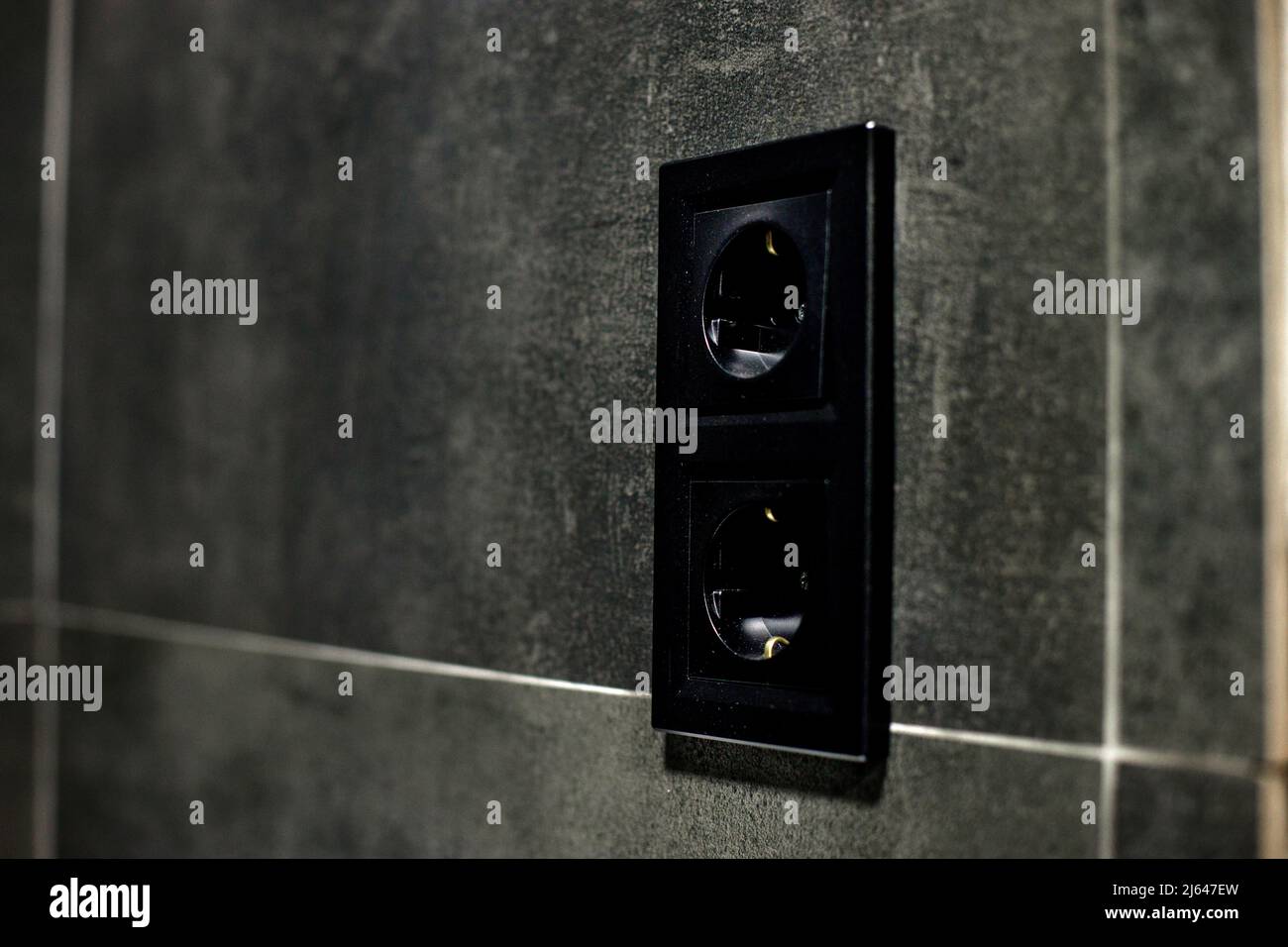 New black rosette on a ceramic tile of black color. Electrical outlet ...