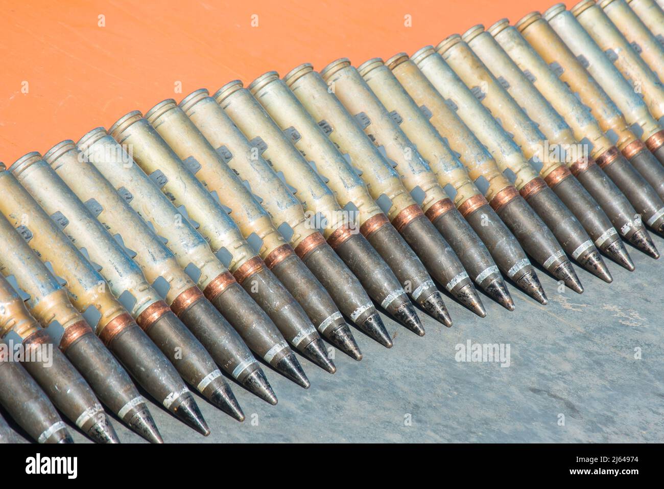 Number of cartridges from machine gun folded in a row on a orange ...