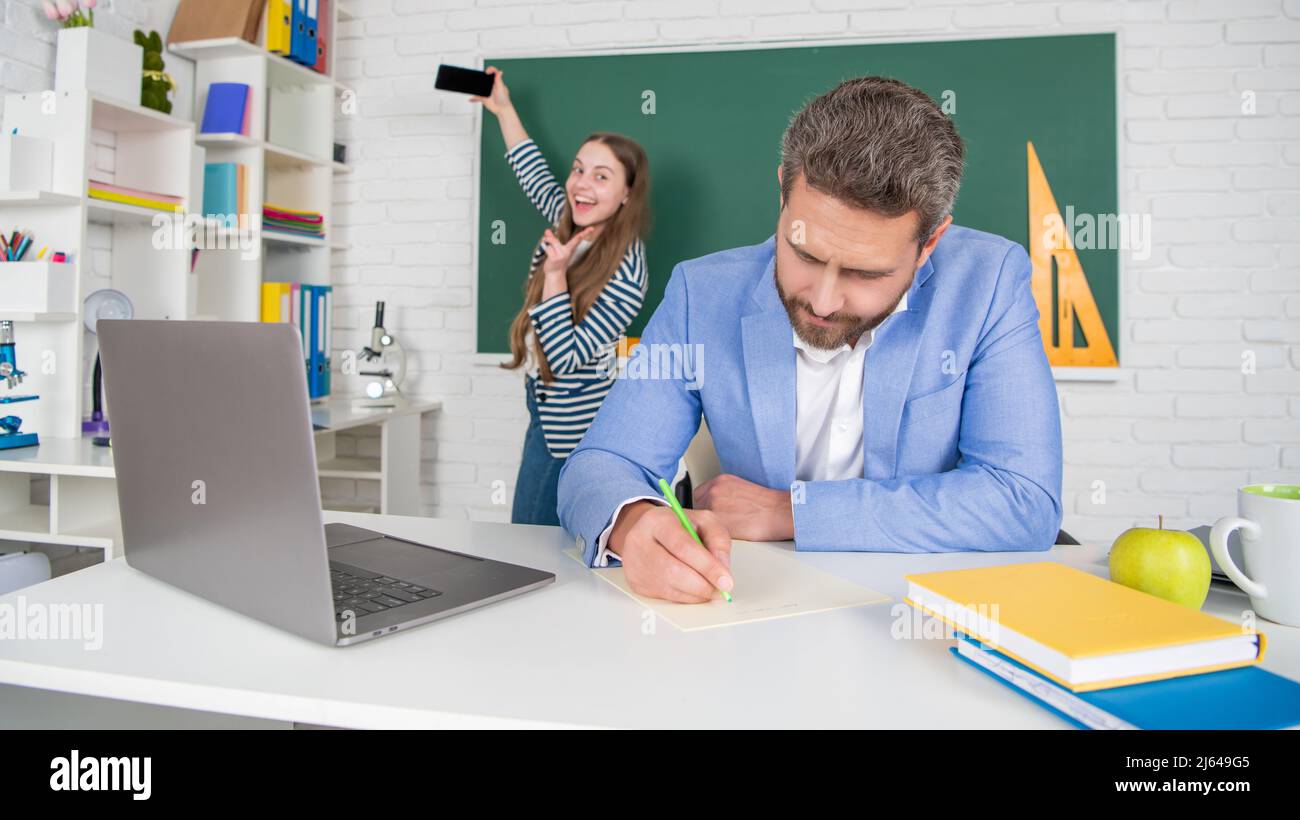 busy school teacher in classroom with selective focus of kid making ...