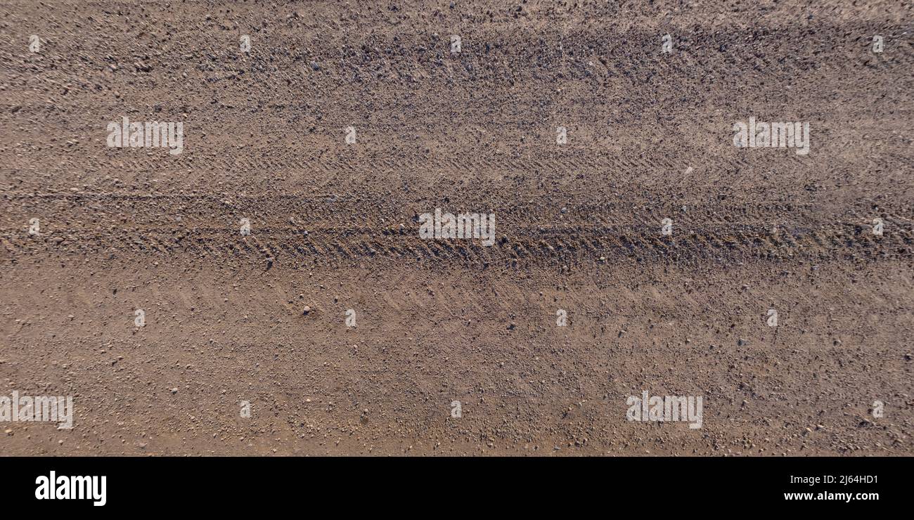 panorama of surface from above of gravel road with car tire tracks ...