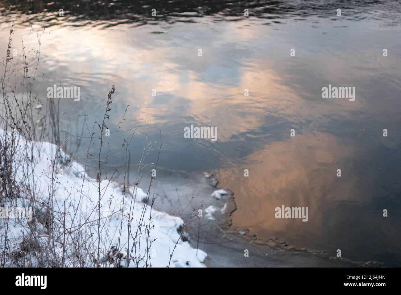 Winter view on cold snowy frozen river shore with dry grass and scenic ...